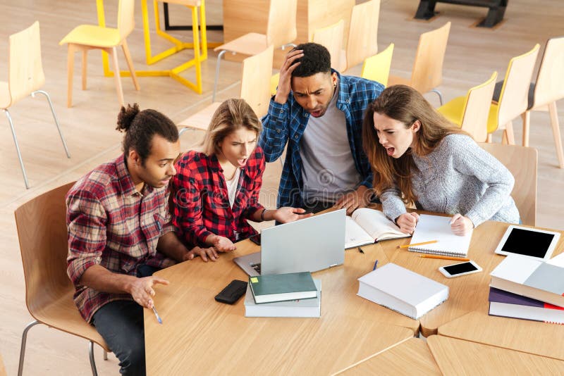 Sad Confused Students Sitting in Library Using Laptop Computer. Stock ...