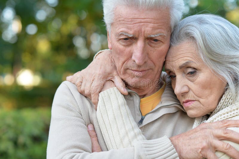 Sad Elderly Couple Standing Embracing Outdoors Stock Image - Image of ...