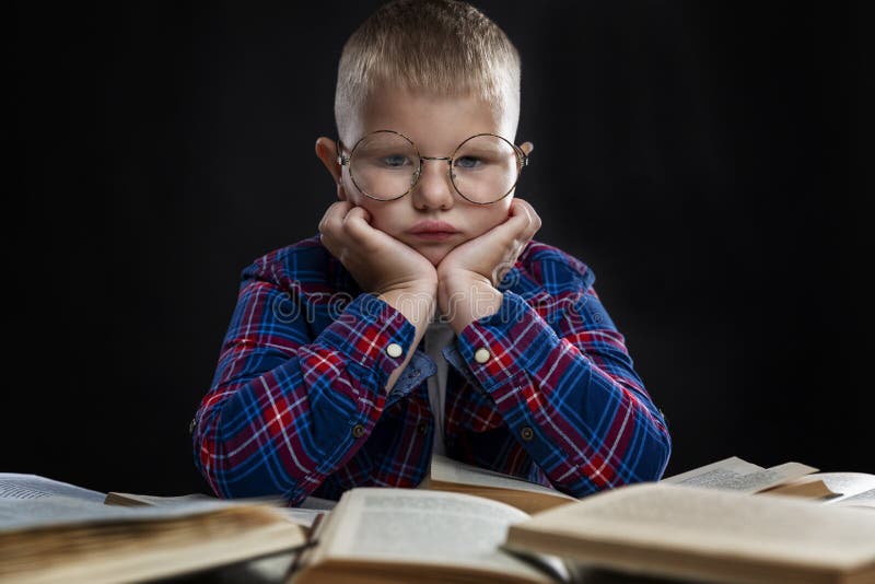 A Sad Fat Boy with Glasses Sits with Books at the Table. Black ...