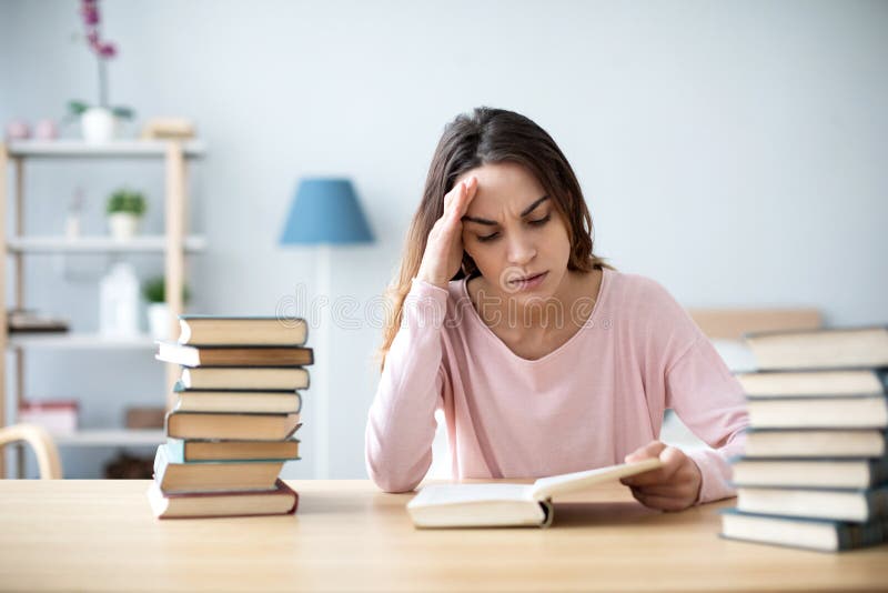 Sad Female Student Reading a Book for the Exam or Doing Homework Stock ...