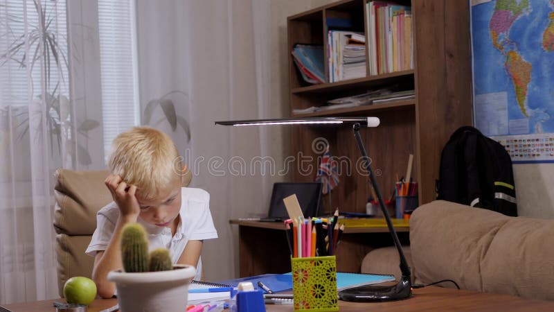 A Sad Little Boy is Crying Sitting at His Desk Over Notebooks and ...