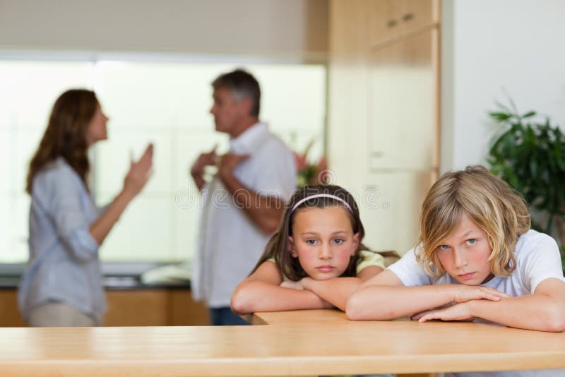 Sad Looking Siblings with Arguing Parents Behind Them Stock Photo ...