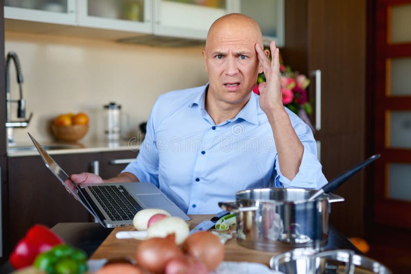 Sad Man Looks into Laptop and while Cooking in Kitchen. Stock Photo ...