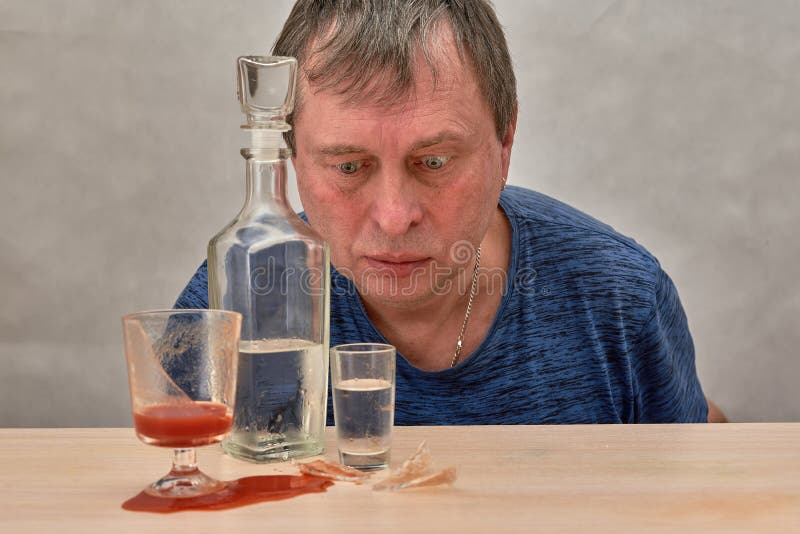 A Sad Man Sits at a Table and Drinks Vodka Alone with Alcohol Addiction ...