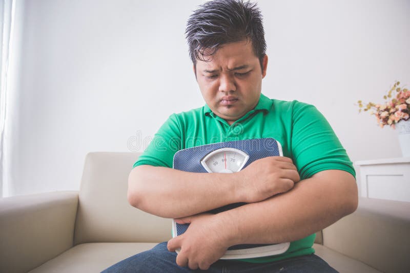 Sad Obese Man Holding a Weight Scale, Thinking about His Weight Stock ...