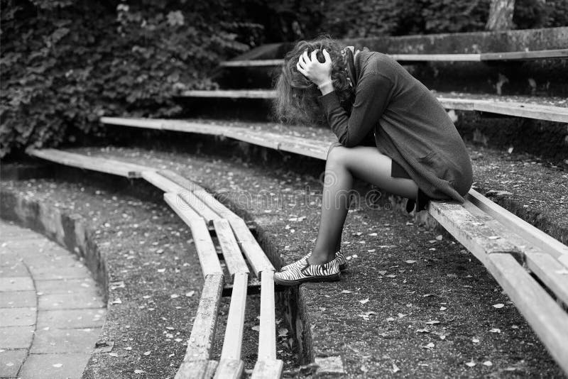 Sad woman sitting on the bench in the park - Stock Image - Everypixel