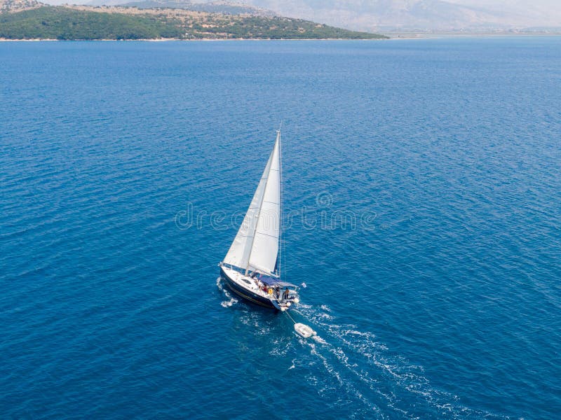 Sailboat on Blue Water with a Small Dinghy Trailing Behind Stock Photo ...