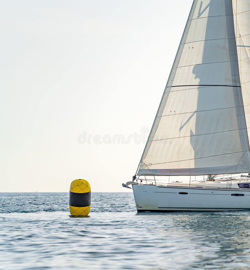 Sailboat Arrives at Buoy Under Clear White Sky for Text Stock Photo ...