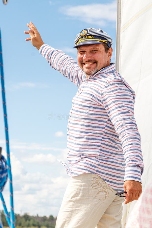 Sailor Man in a Cap on a Boat Under Sail Against the Sky and Water ...