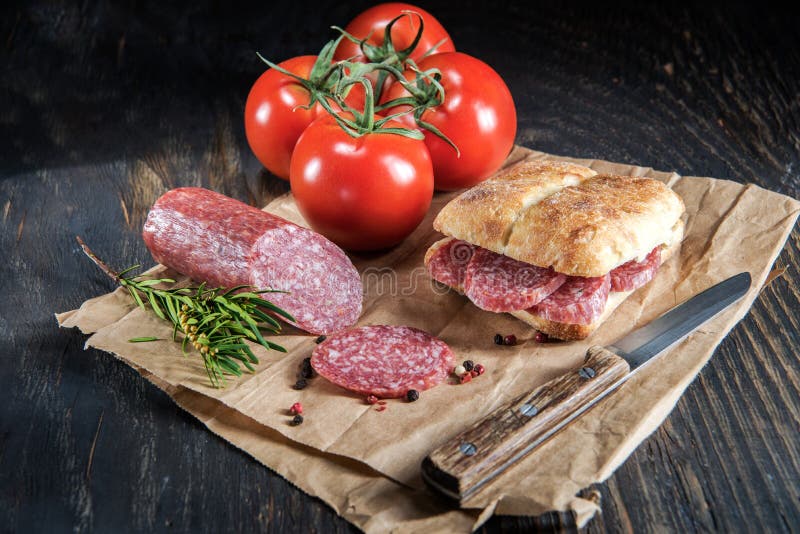 Salami Sandwich on Wrapping Paper with Cut Pieces and Knife Stock Image ...
