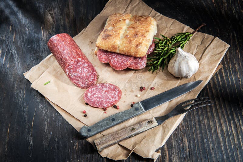 Salami Sandwich on Wrapping Paper with Cut Pieces and Knife Stock Image ...