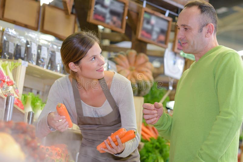 Sales Assistant with Customer Holding Carrots Stock Image - Image of ...