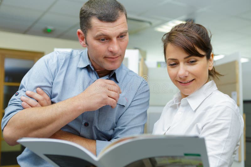 Sales Assistant Looking at Catalogue with Customer Stock Photo - Image ...