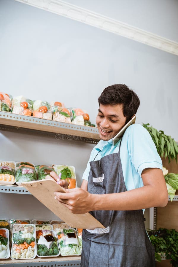 Sales Man Calling while Taking Notes on Vegetable Products Background ...