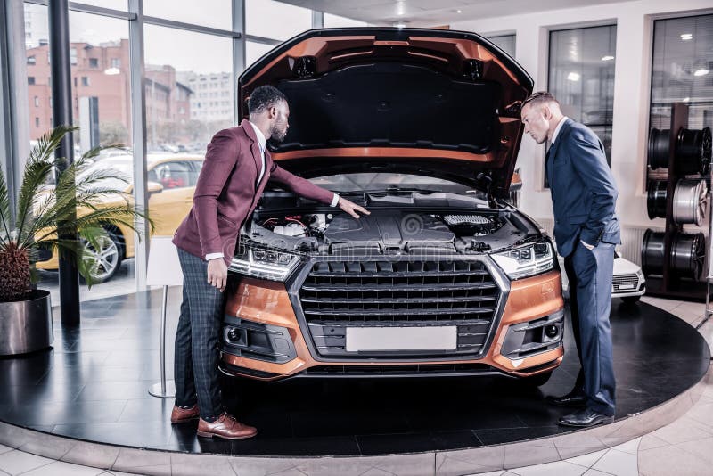 Sales Manager Opening Up the Boot of the Car while Telling Client about ...