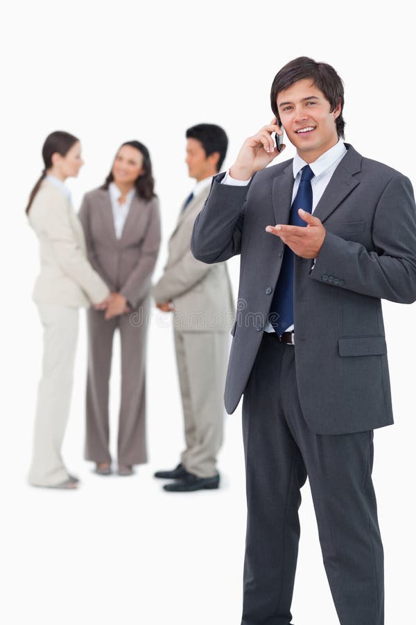Salesman Talking on Cellphone with Colleagues Behind Him Stock Image ...