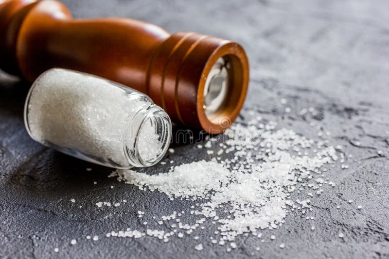 Salt in Glass Bottle with Saltcellar on Black Stone Table Background ...