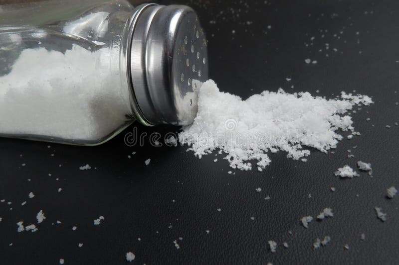 Salt Glass Shaker and Pile of Spilled Salt on a Black Table Stock Image ...