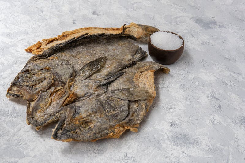 Salted Dry Raw Cod on a Light Textured Background with a Well of Salt ...