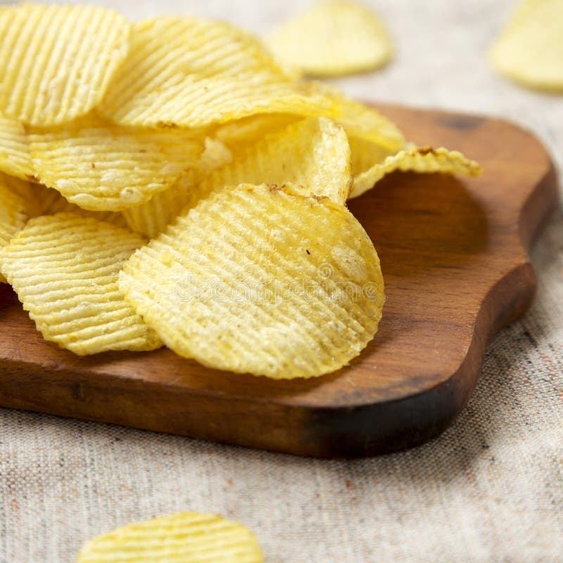 Salted Wavy Potato Chips on a Rustic Wooden Board, Side View. Close-up ...