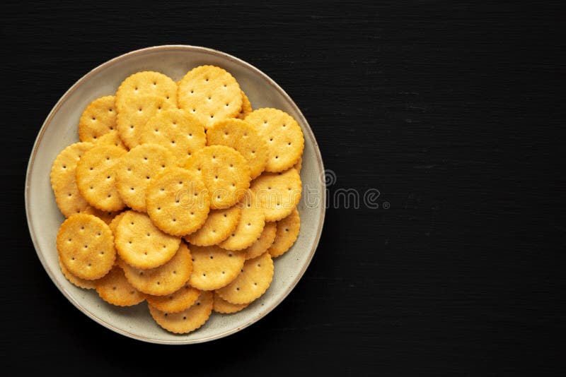 Salty Round Crackers on a Plate on a Black Surface, Top View. Flat Lay ...
