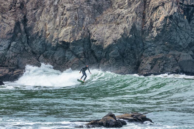 A Surfer Rides a Wave with Cliffs in the Background in San Francisco ...