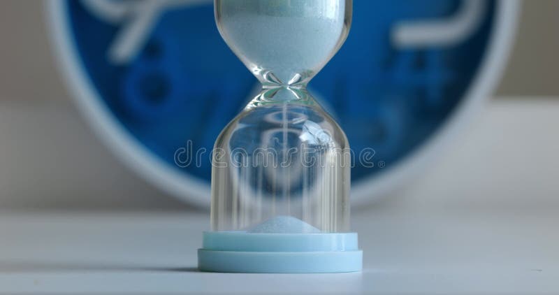 Sand Flows through Hourglass Table before Wall Clock, Moving Second ...