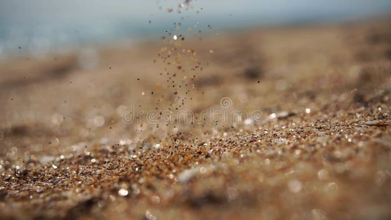Sand Flows in Slow Motion Against the Bokeh Background of the Beach and ...