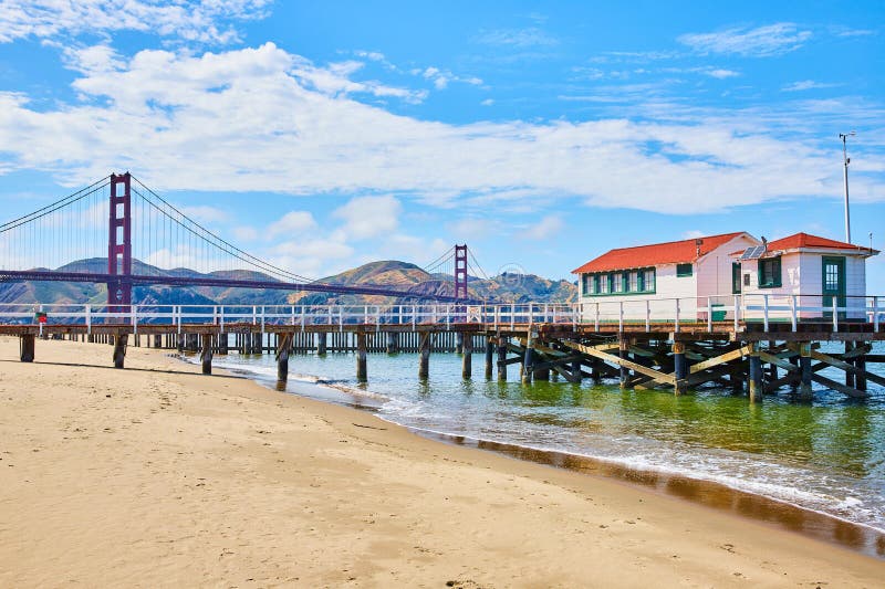 Sandy Beach with Lapping Waves Around Pier with Tiny Shack and View of ...