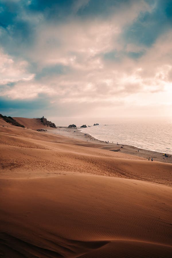 A Sandy Hill in Front of the Coastline with People and a Majestic ...