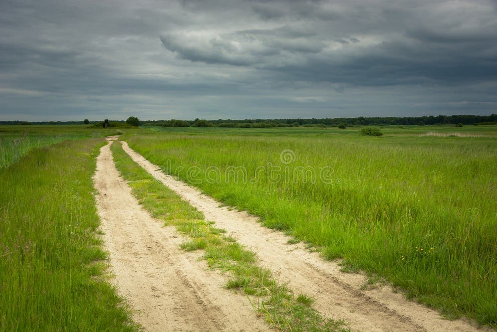 Sandy Road and Green Fields, Dark Clouds on the Sky Stock Photo - Image ...