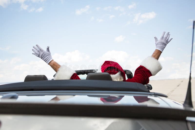 Santa with Arms Raised in Convertible Against Sky Stock Photo - Image ...