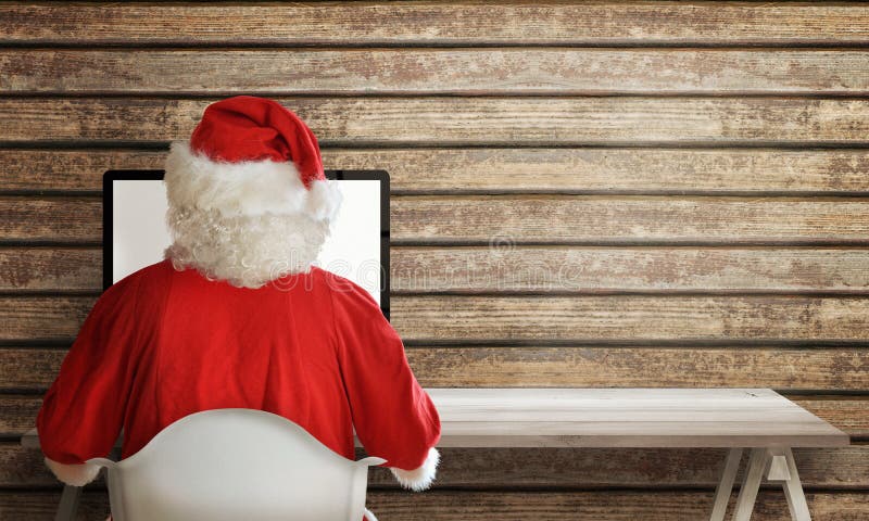 Santa Claus Work on Computer at His Home. Wooden Wall and Table with ...