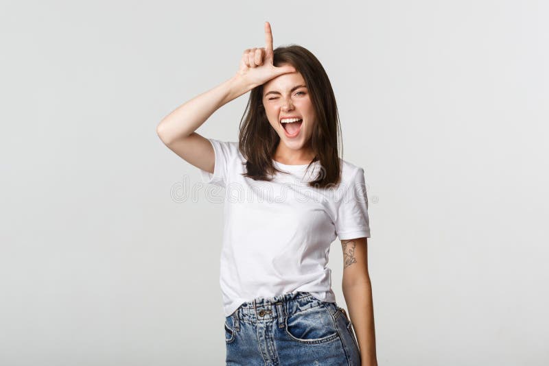 Sassy Good Looking Girl Smiling And Mocking Person Showing Loser Gesture On Forehead Stock