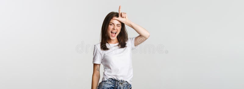 Sassy Good Looking Girl Smiling And Mocking Person Showing Loser Gesture On Forehead Stock