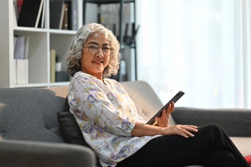 Satisfied Middle Aged Using Digital Tablet on Comfortable Sofa at Home ...