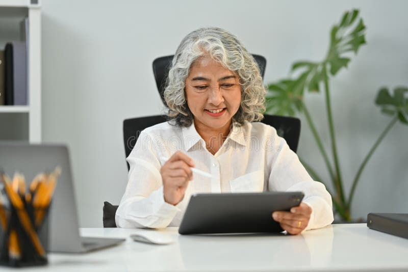 Satisfied Middle Aged Woman Browsing Wireless Internet on Tablet at ...