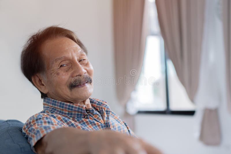Satisfied Old Man Looking at Camera and Smiling while Sitting on Sofa ...