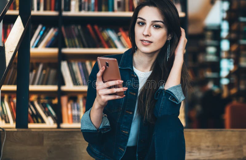 Satisfied Young Woman Using Smartphone in Library Stock Photo - Image ...