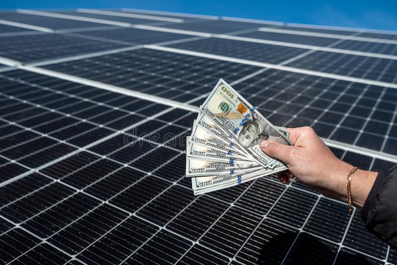 Saving Money with Solar Energy and Solar Panels. Hand with Dollars in ...