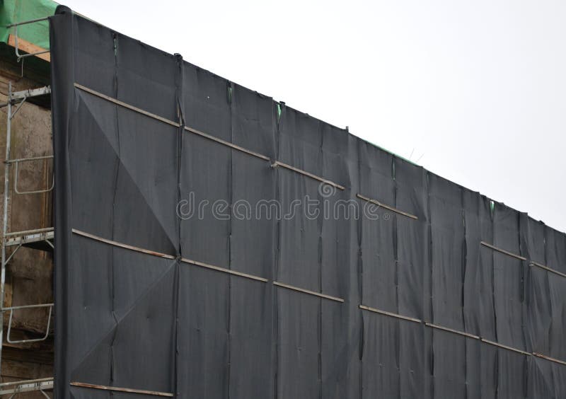 Scaffolding of a Repaired House on the Street. is Covered with a Green ...