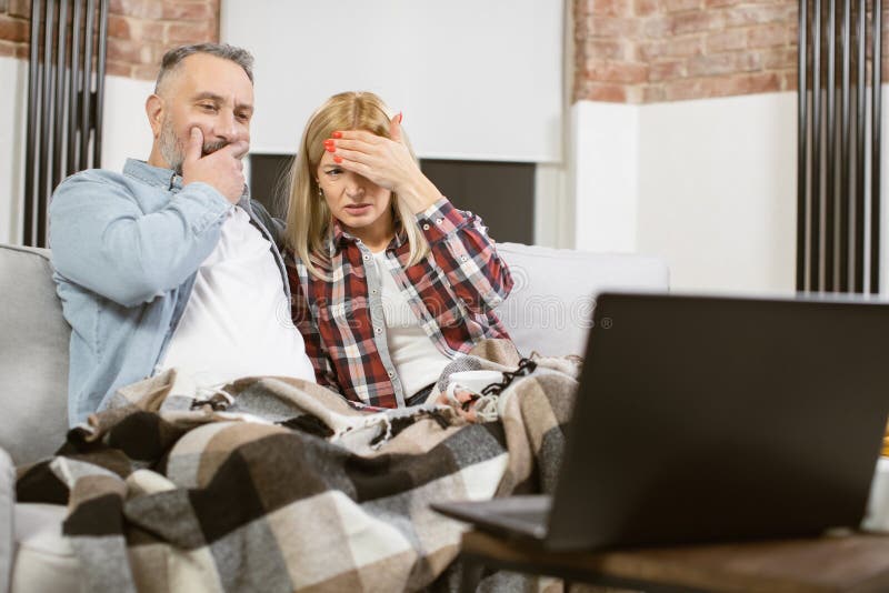 Scared Married Couple Watching Horror Movie On Laptop Stock Image