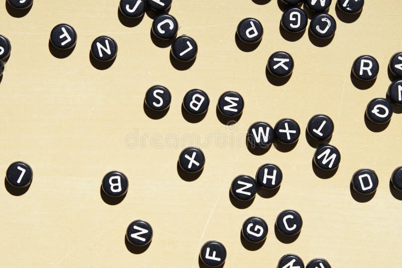 Scattered Black Alphabet Letters on Beige Surface with Randomized Flat ...