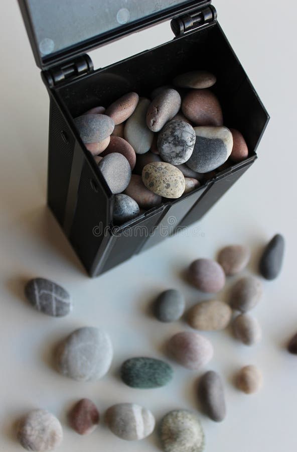Scattered Pebbles and Black Plastic Container Full of Smooth Pebbles on ...