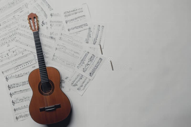 Scattered Sheet Music with an Acoustic Guitar and a Tuning Fork on a ...