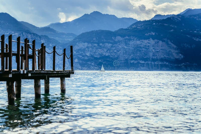 Scenery with Wooden Dock Pier Extending Over Blue Lake Water and ...