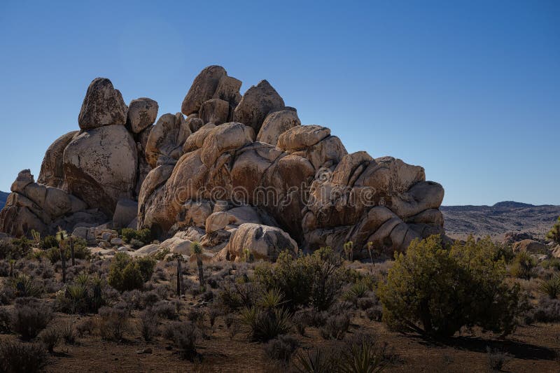 A Large Rock in the Middle of a Desert Landscape with Trees and Shrubs ...
