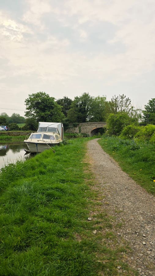 Scenic Riverside View with a Boat Moored Along a Grassy Path and a ...