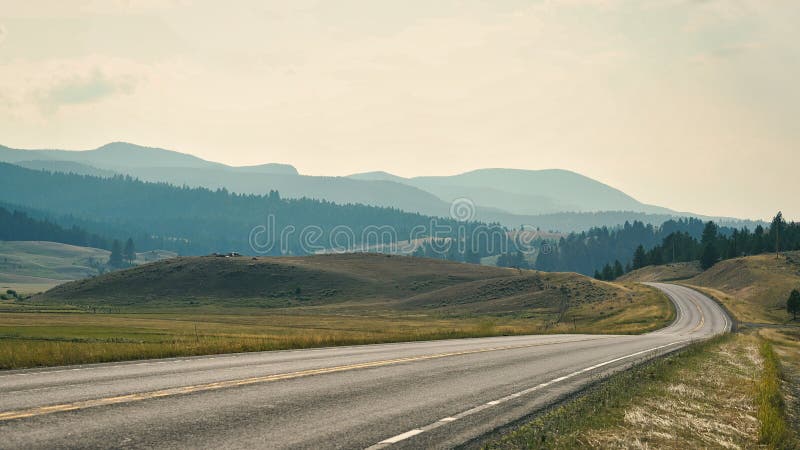Scenic Rural Road Winding through a Lush Valley with Distant Mountains ...