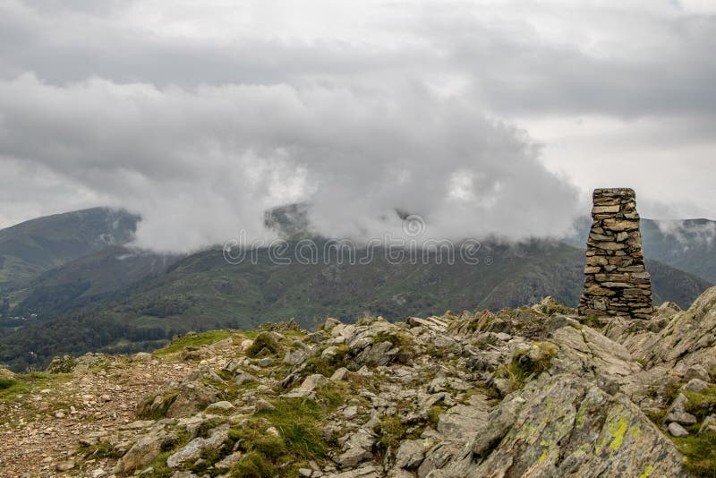 Scenic Shot of a Stone Tower on a Rocky Field with Mountains Touching ...